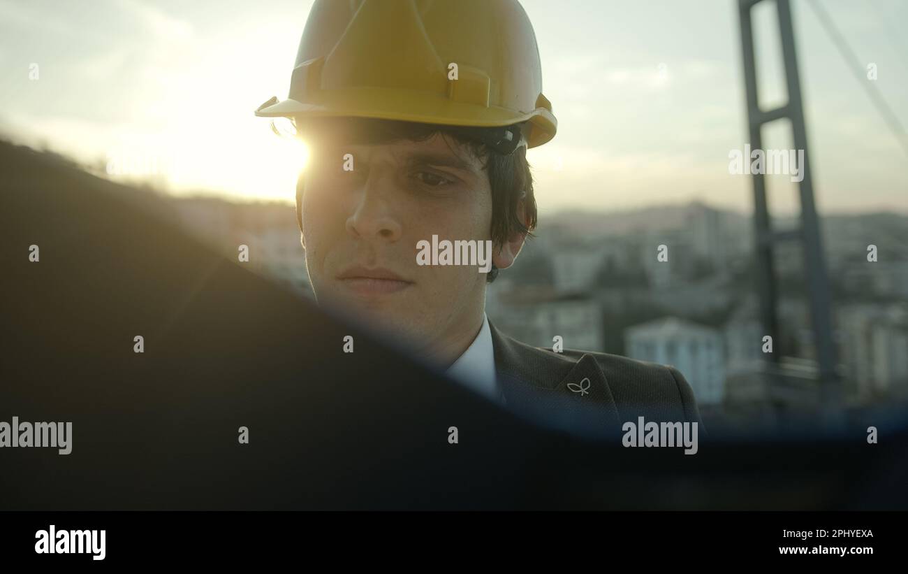 A Young Suit-Clad Engineer or Contractor Reviewing Blueprints and ...