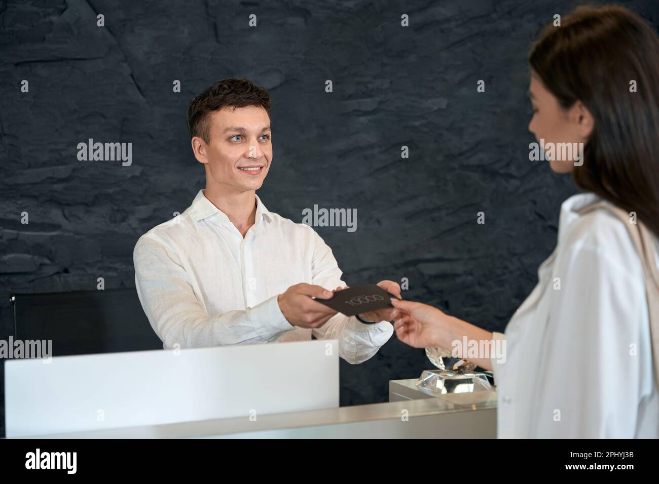 Smiling male offering brochure with services to female Stock Photo - Alamy