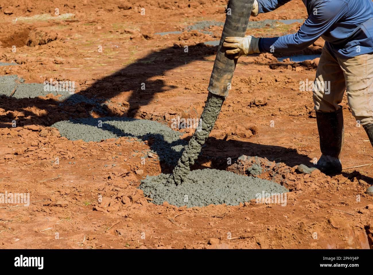 Concrete is poured for laying foundation of building by worker using an ...