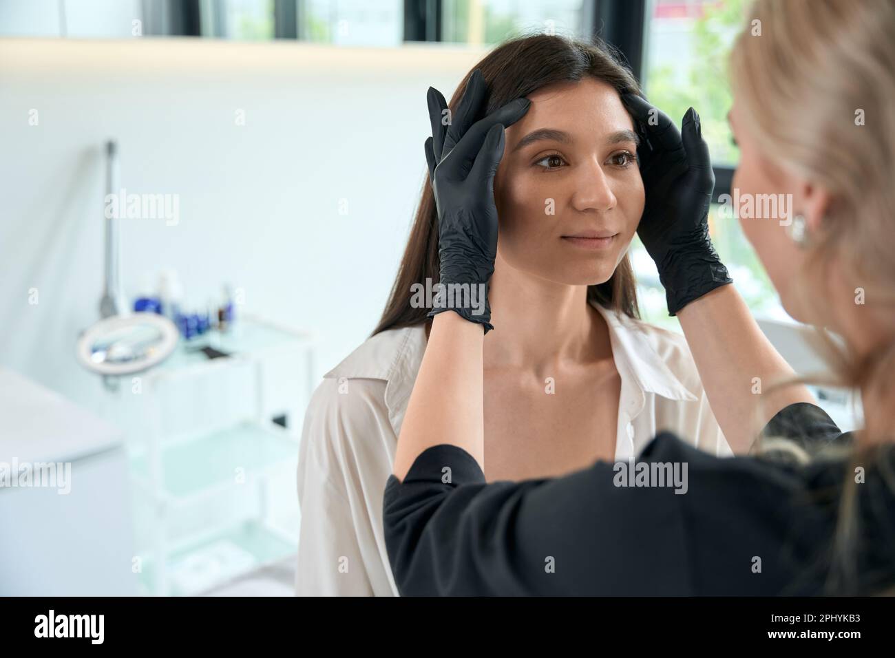 Dermatologist examining lady face before treatment in hospital Stock ...