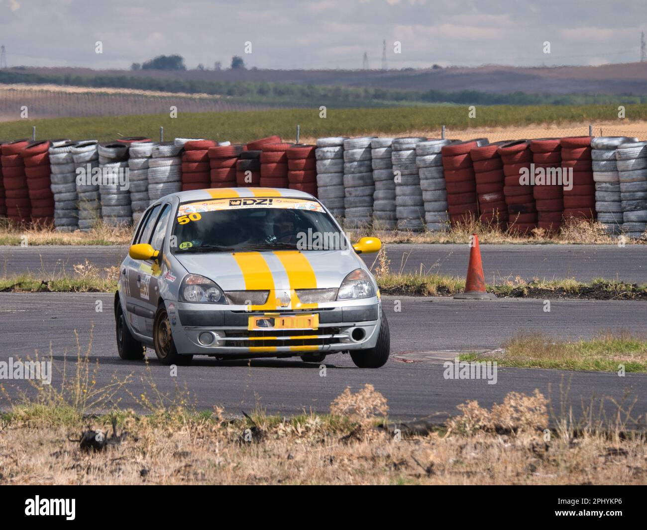 A silver race car with a yellow stripe on the road during the race ...