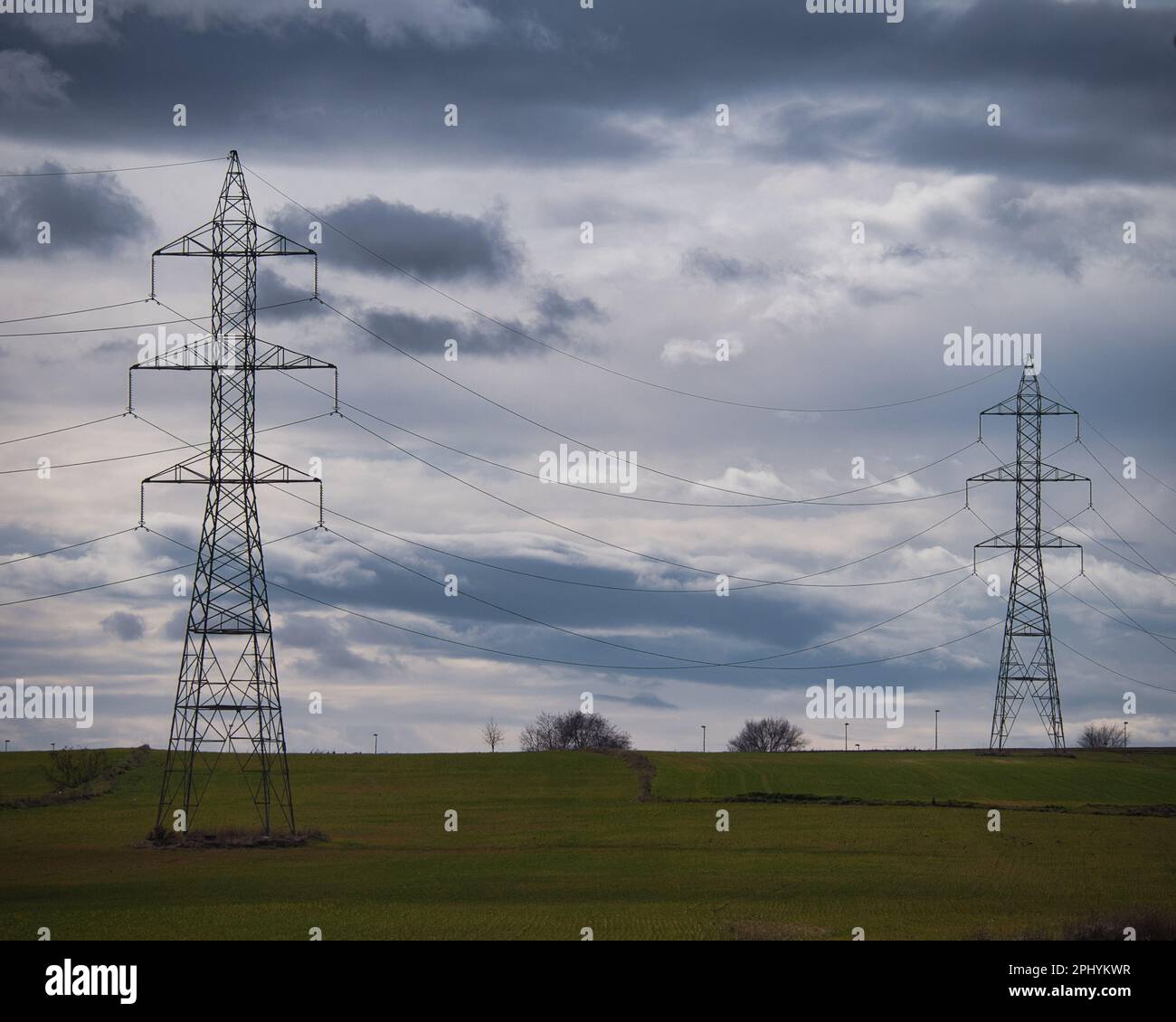 The power lines crossing a grassy landscape, with white clouds in the ...