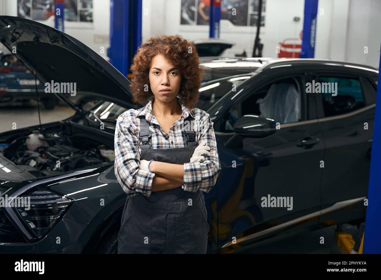 Multiracial curly employee of car repair shop stands by car Stock Photo ...