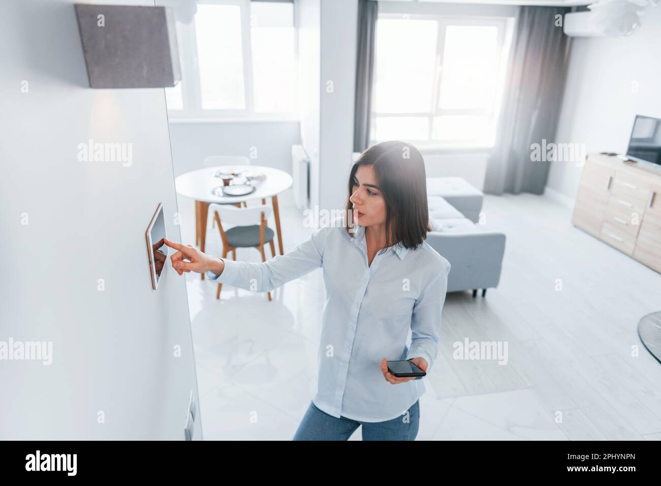 Uses tablet that is mounted in the wall. Young woman is indoors in ...