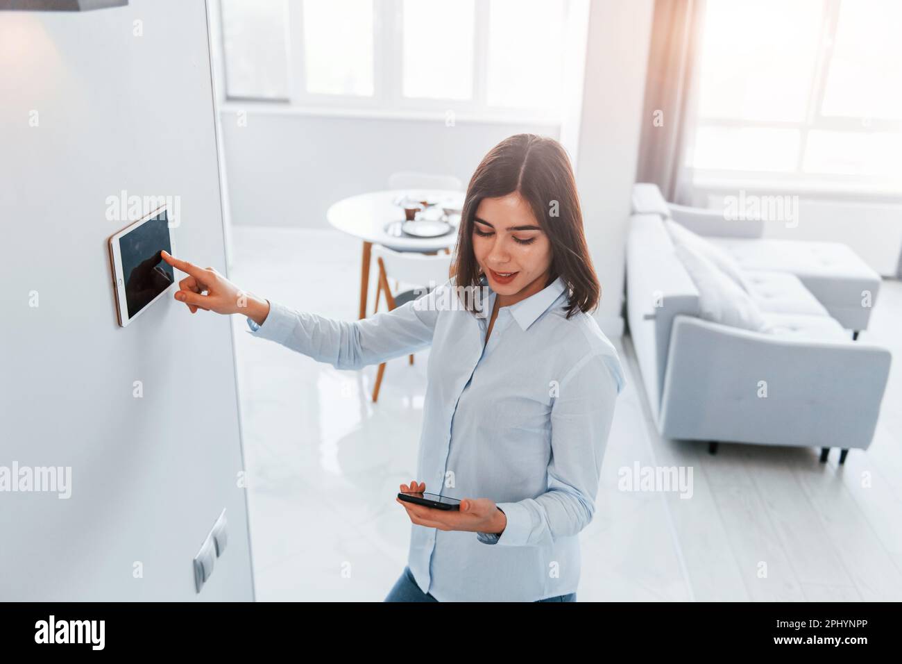 Uses tablet that is mounted in the wall. Young woman is indoors in ...