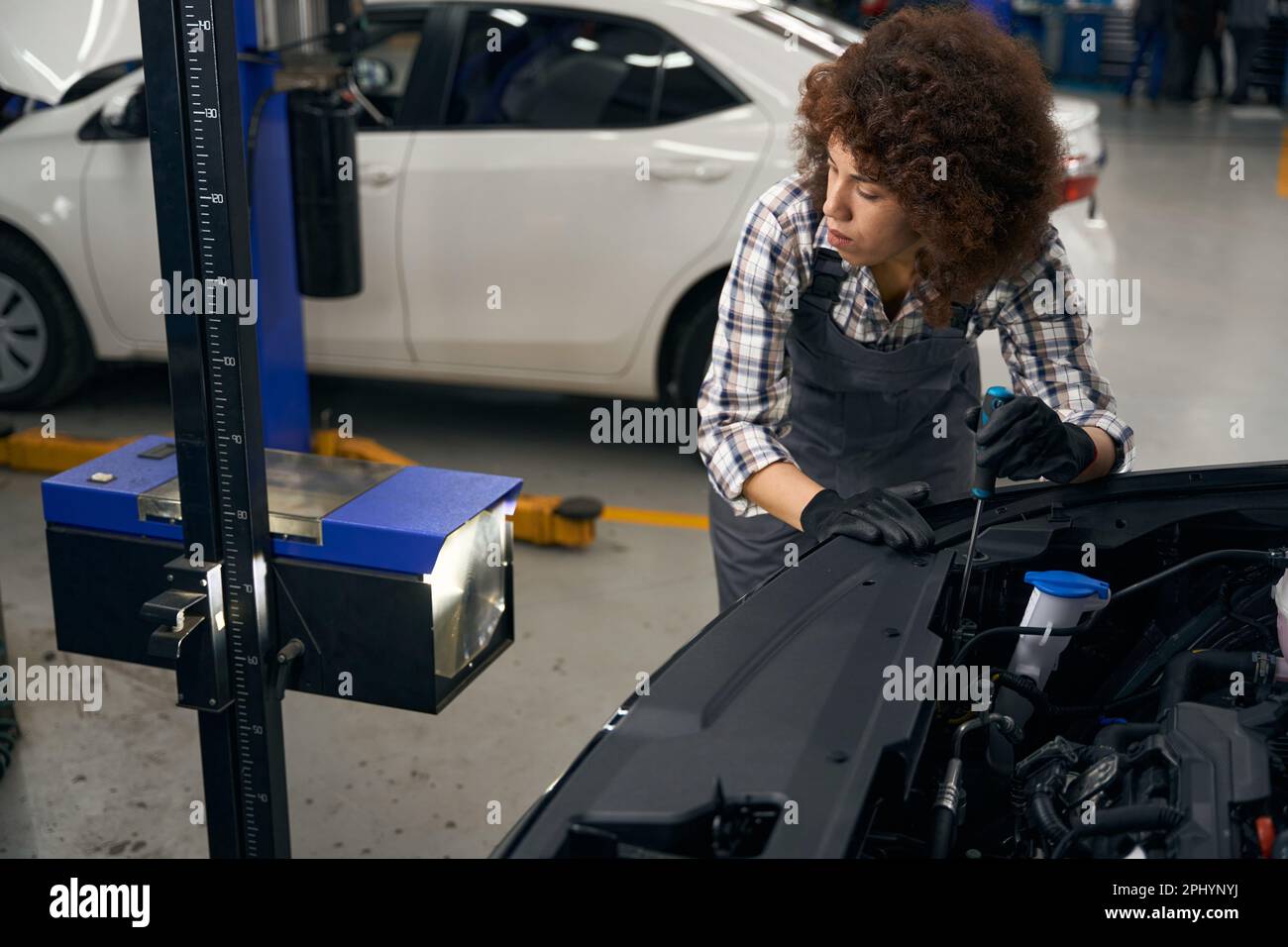 Young female employee of car repair shop uses modern equipment Stock ...