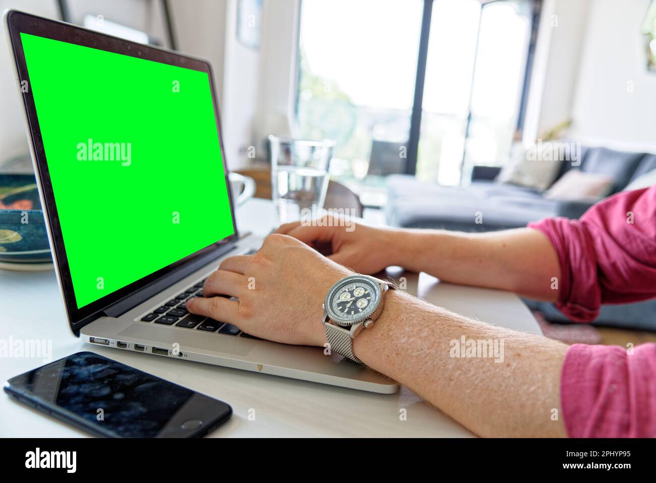 Young professional man using a laptop with a green screen - wearing a ...
