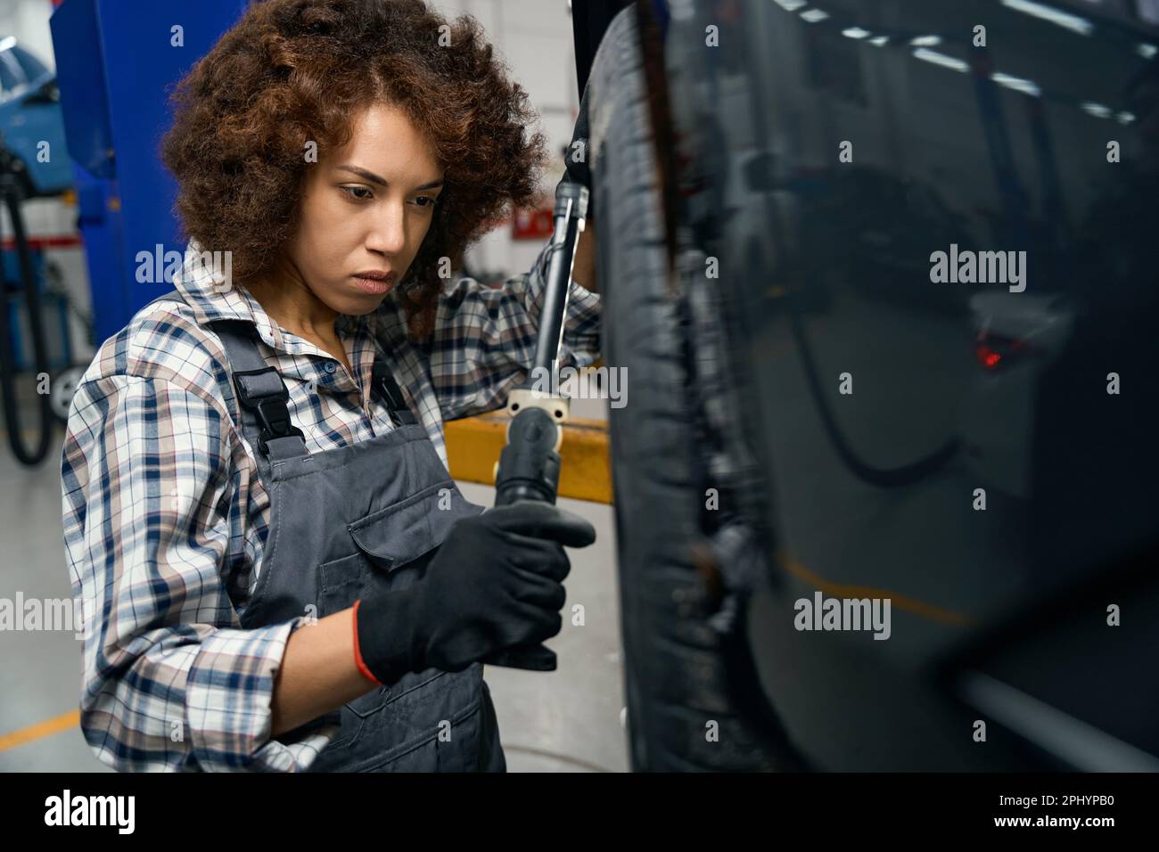 Young auto repairman in work clothes looks wheel of car Stock Photo - Alamy