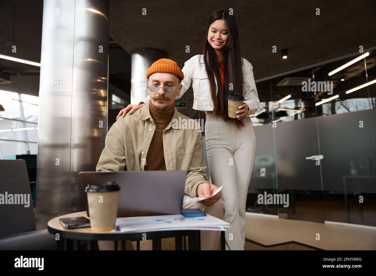 Corporate worker working on portable computer supervised by office ...