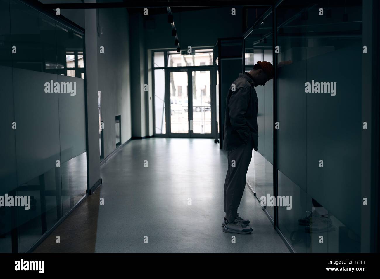 Depressed company employee standing alone in dark office corridor Stock ...