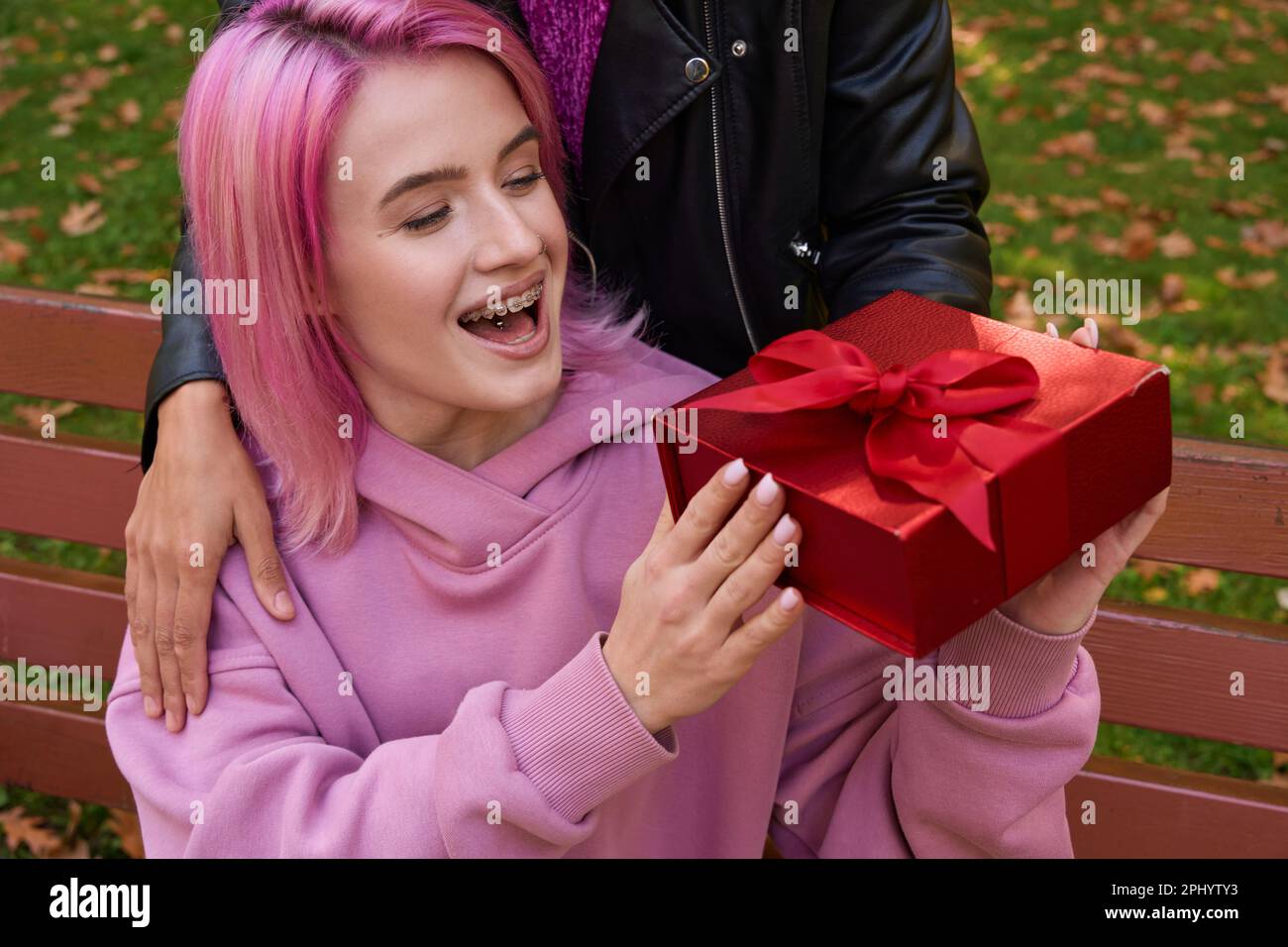 Happy lady receiving present from female companion outdoors Stock Photo ...