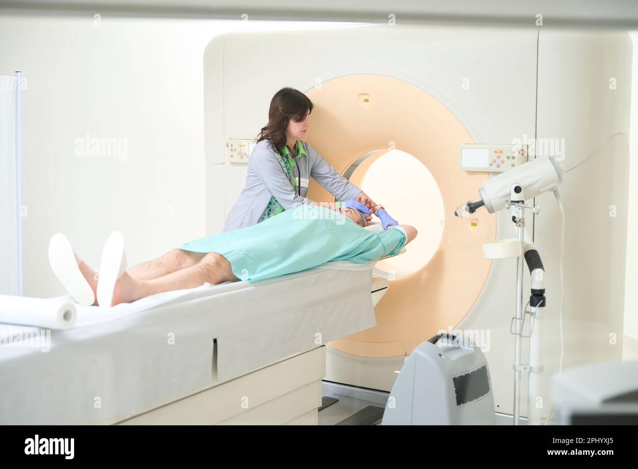 Doctor correcting patient hands before MRI scan in clinic Stock Photo ...