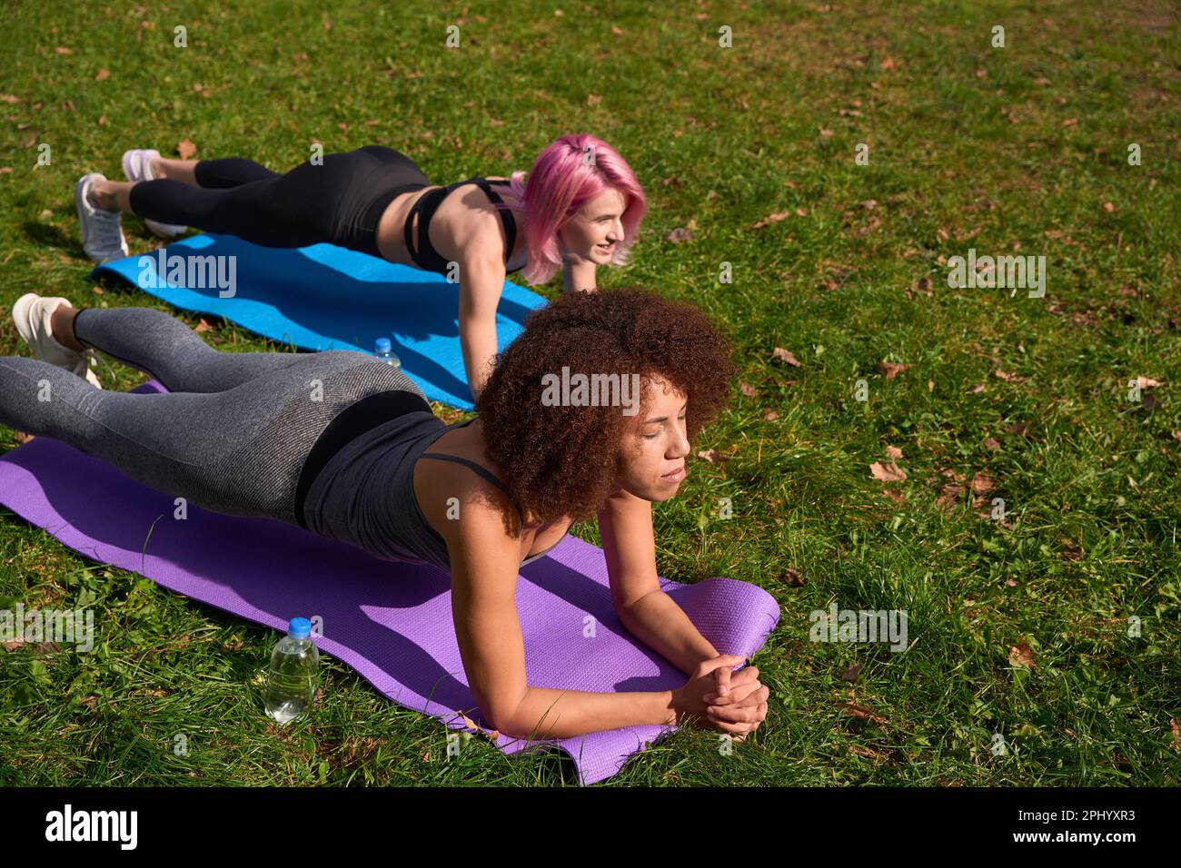 Two young interracial female athletes doing isometric core exercise ...