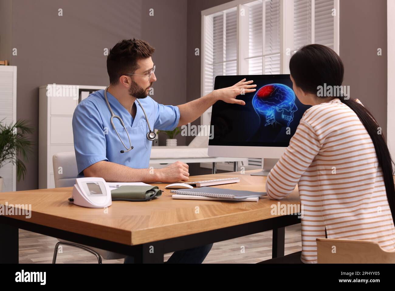 Neurologist showing brain scan to young woman in clinic Stock Photo - Alamy