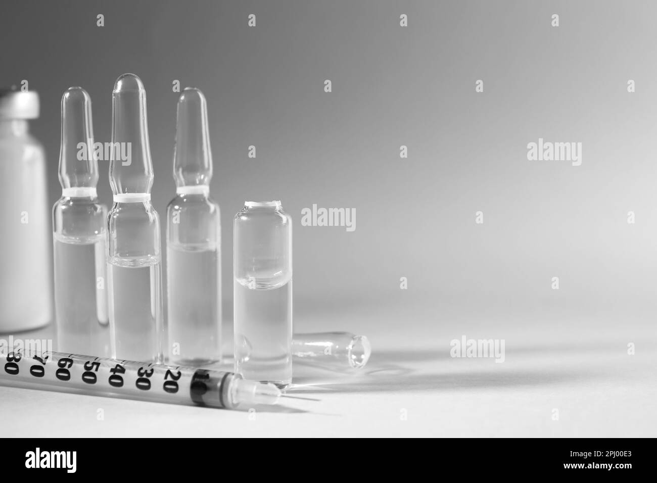 Pharmaceutical ampoules and syringe on light grey background. Space for ...