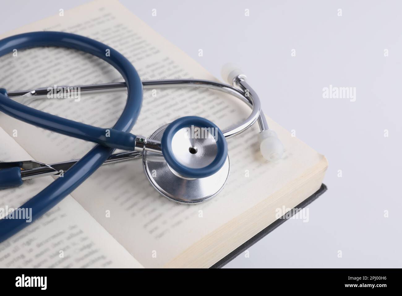 Open student textbook and stethoscope on white background, closeup ...