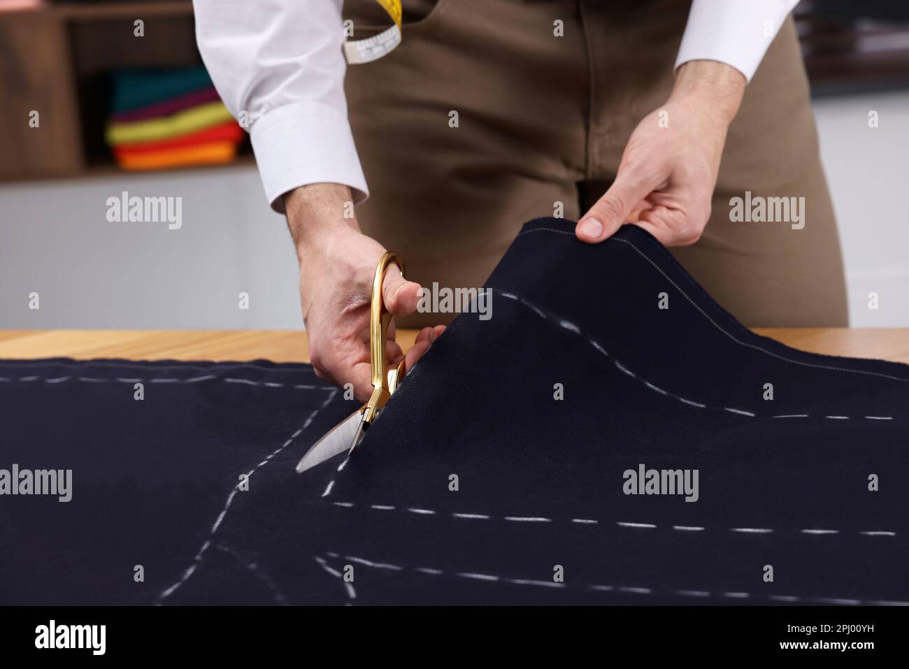 Dressmaker cutting fabric by following chalked sewing pattern in ...