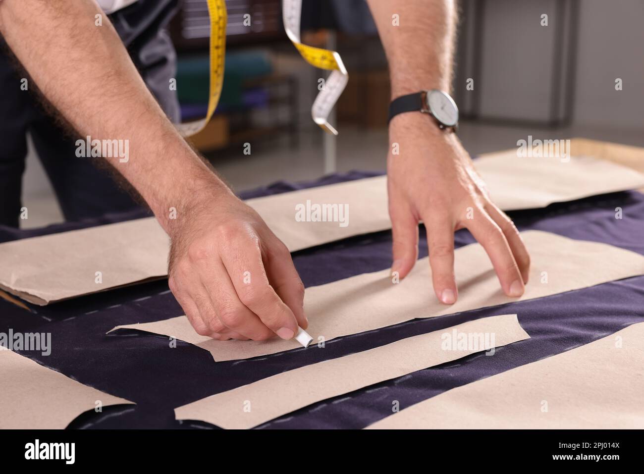 Professional tailor marking sewing pattern on fabric with chalk at ...