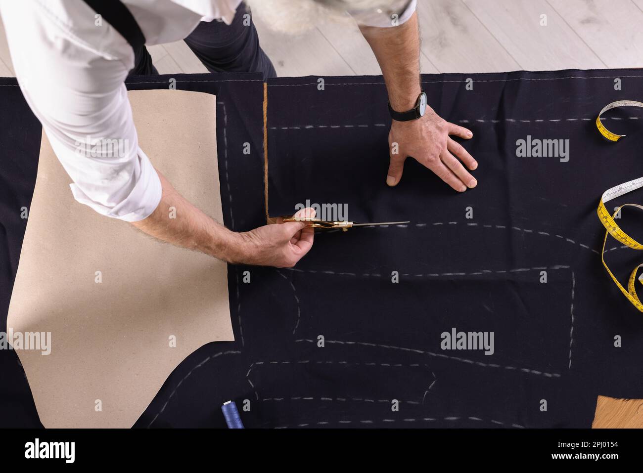Professional tailor cutting fabric by following chalked sewing pattern ...