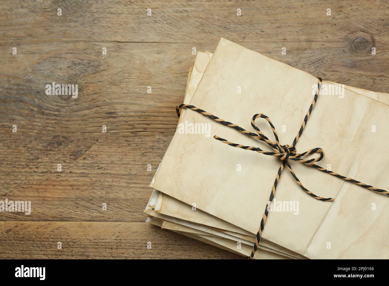 Stack of old letters tied with string on wooden table, top view. Space ...