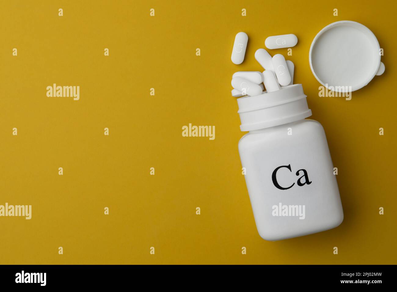 Calcium supplement pills and overturned jar on yellow background, flat ...