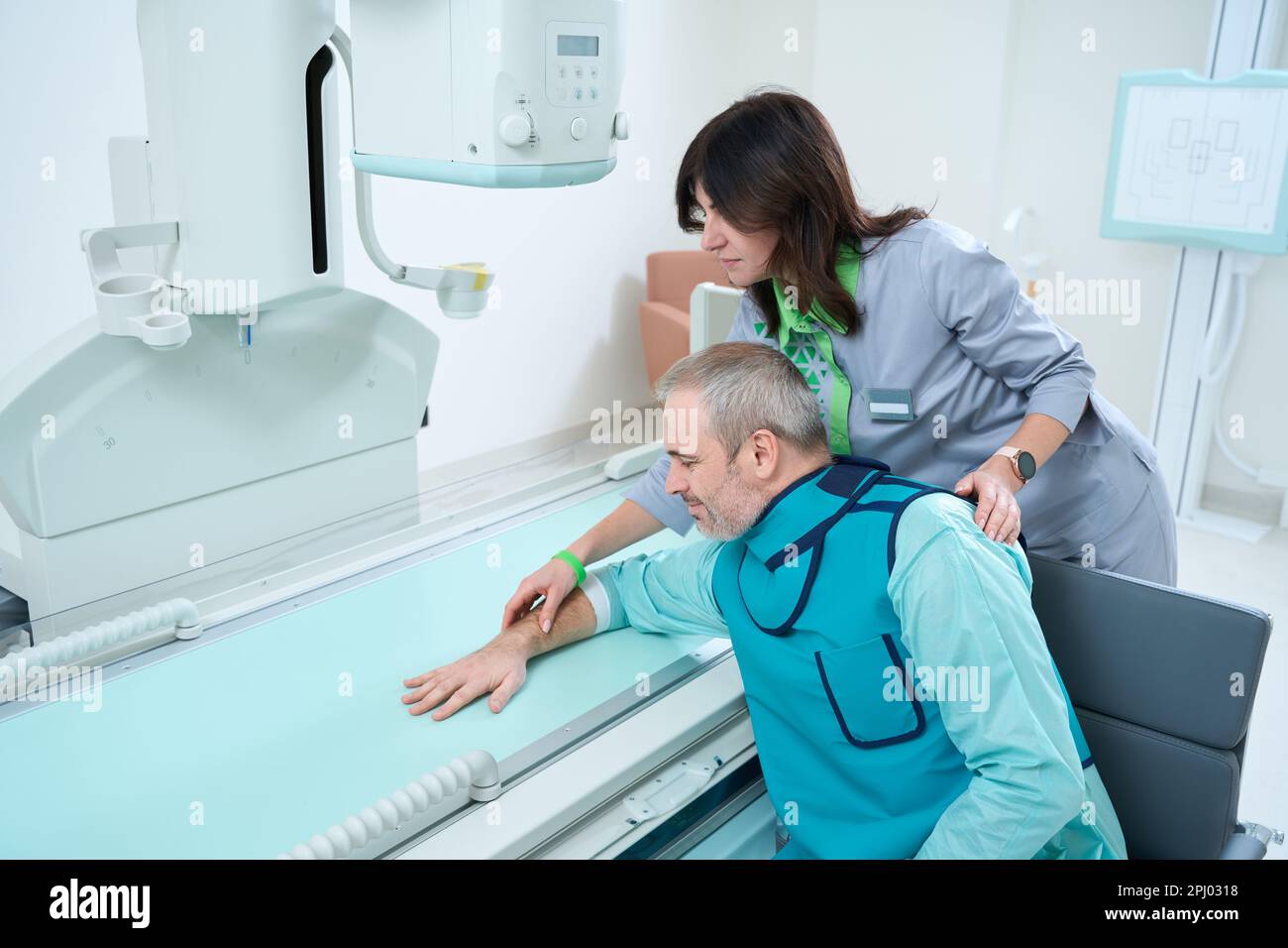 Doctor standing and helping patient to making x-ray at radiology room ...