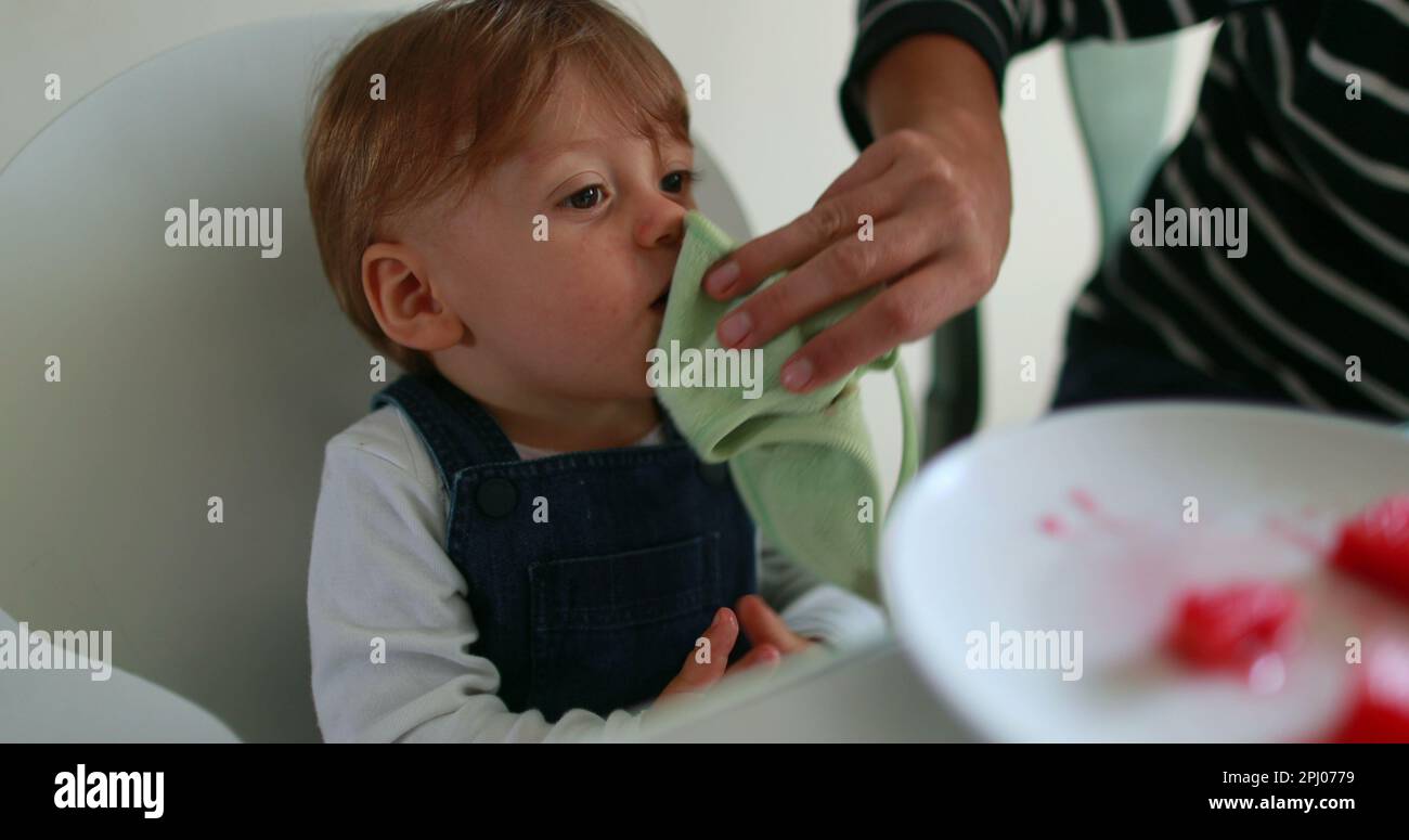 Infant one year old eating dessert, baby clapping hands. mother wiping ...