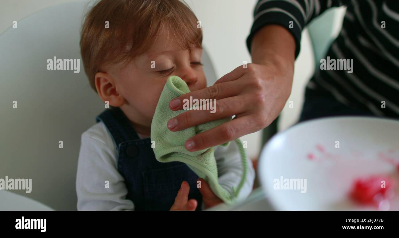 Infant one year old eating dessert, baby clapping hands. mother wiping ...