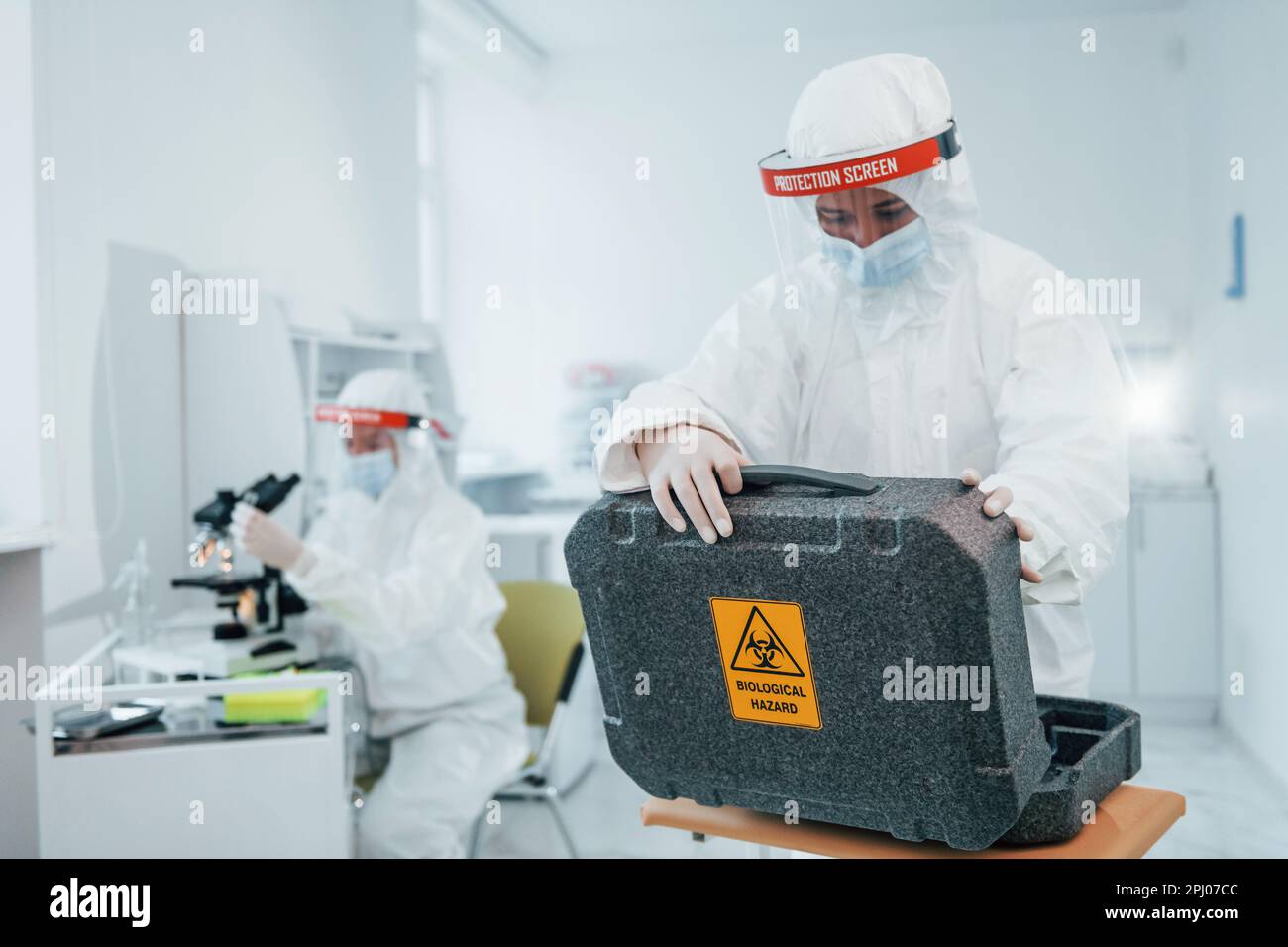 With biological hazard case. Female medical workers in protective ...