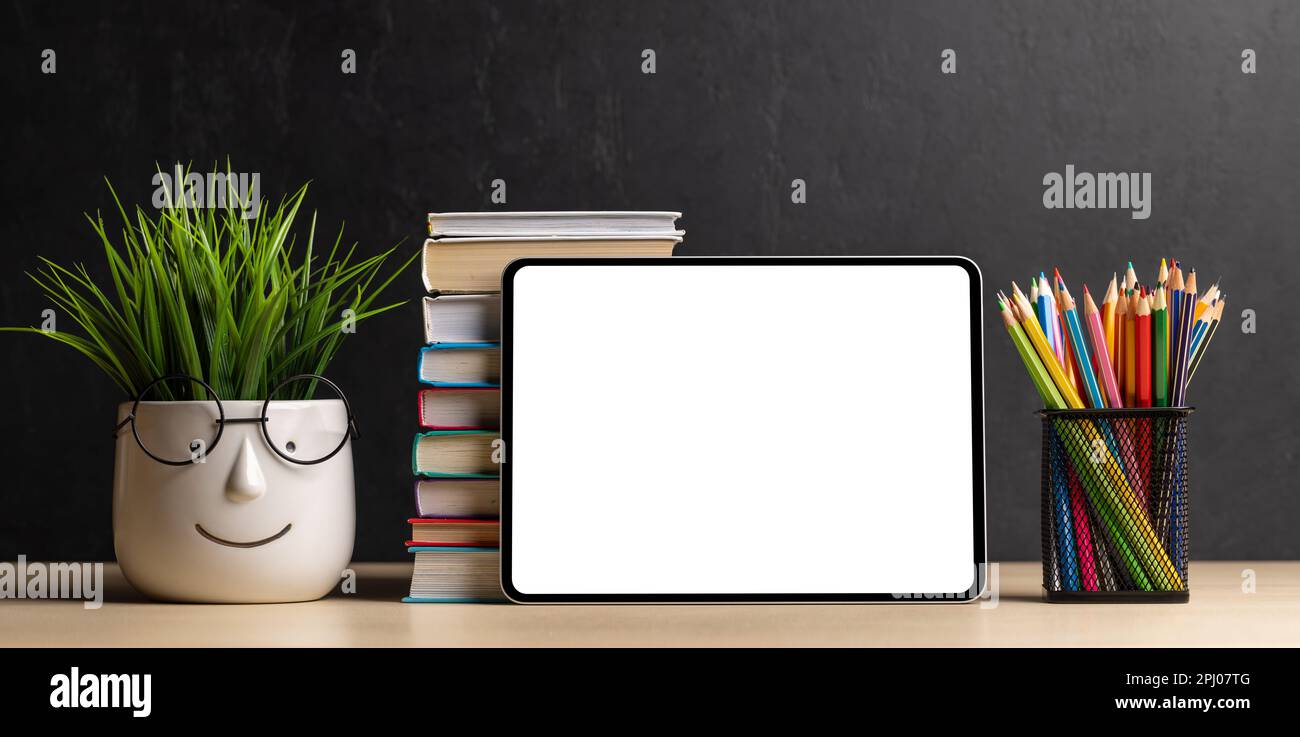 Tablet with colorful pencils and stack of books. With blank screen for ...