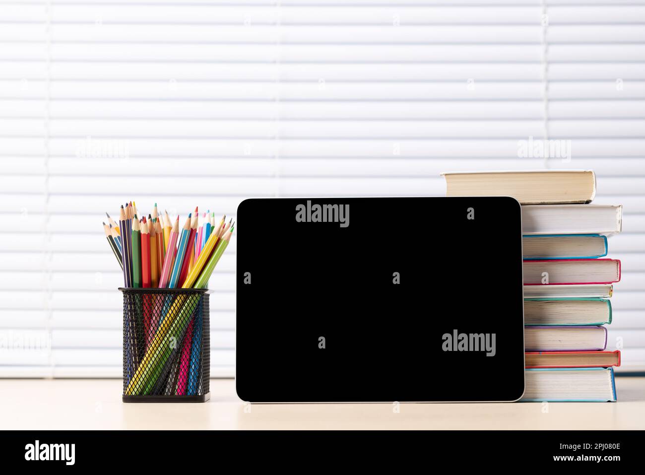Tablet with colorful pencils and stack of books. With blank screen for ...