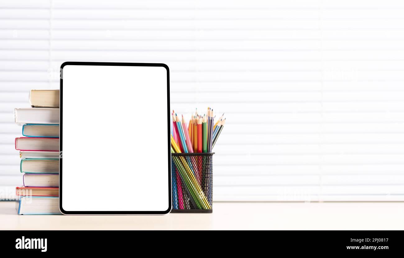 Tablet with colorful pencils and stack of books. With blank screen for ...