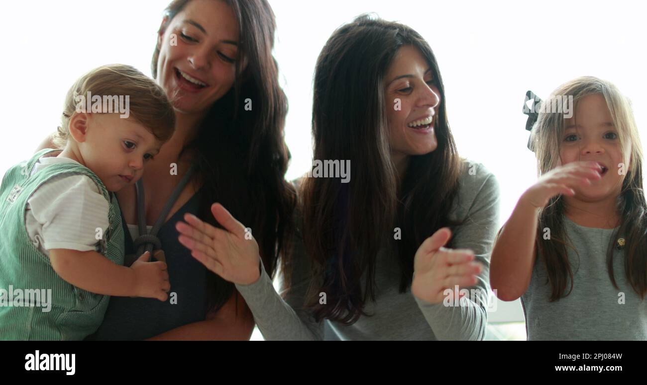 Happy family sisters clapping hands singing Stock Photo - Alamy
