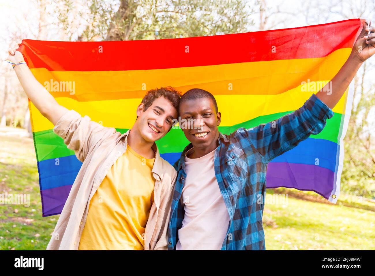 Portrait of multiethnic gay male couple holding a rainbow lgbt symbol ...