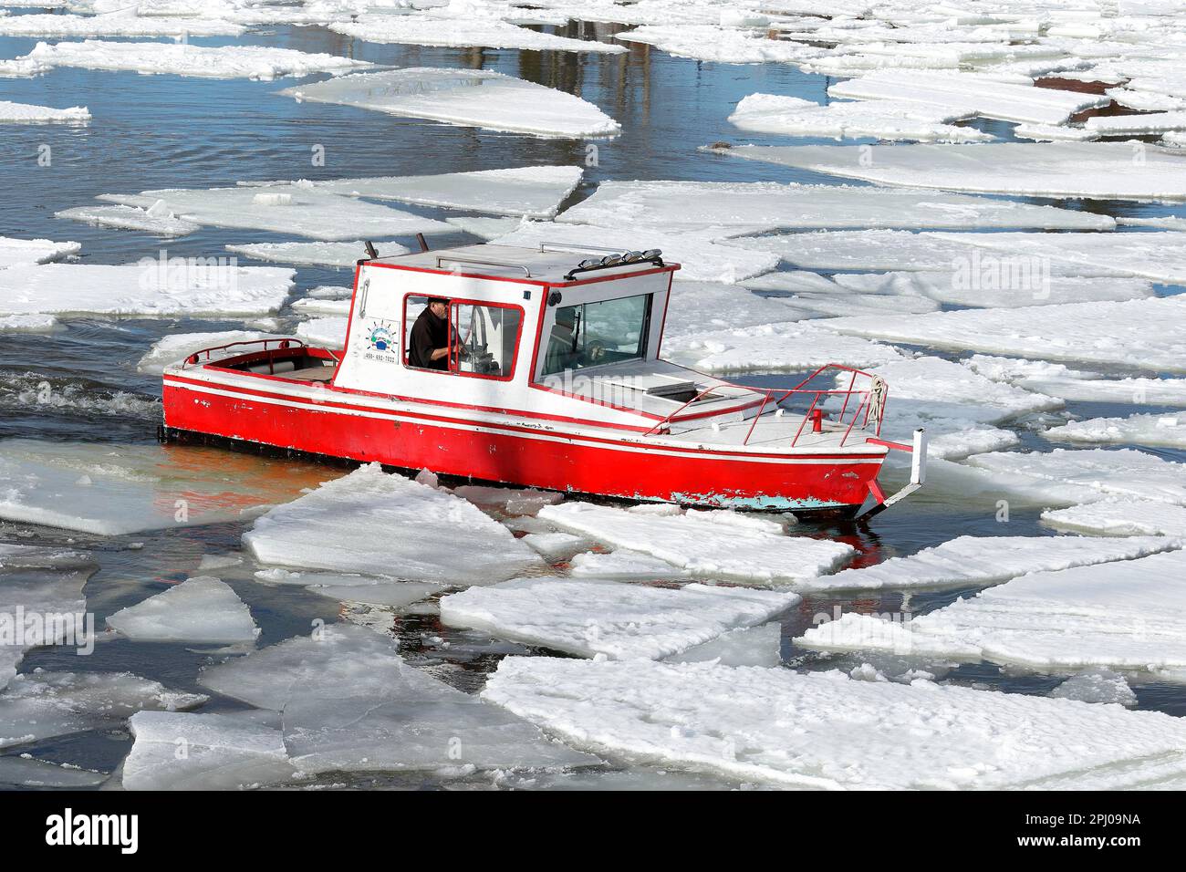 Small red boat between ice sheets, Chateauguay River, Province of ...
