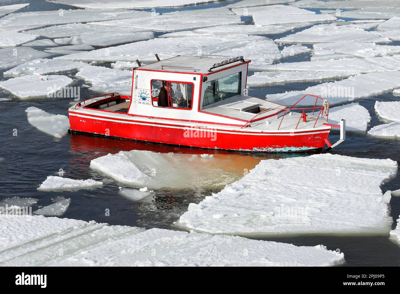Small red boat between ice sheets, Chateauguay River, Province of ...