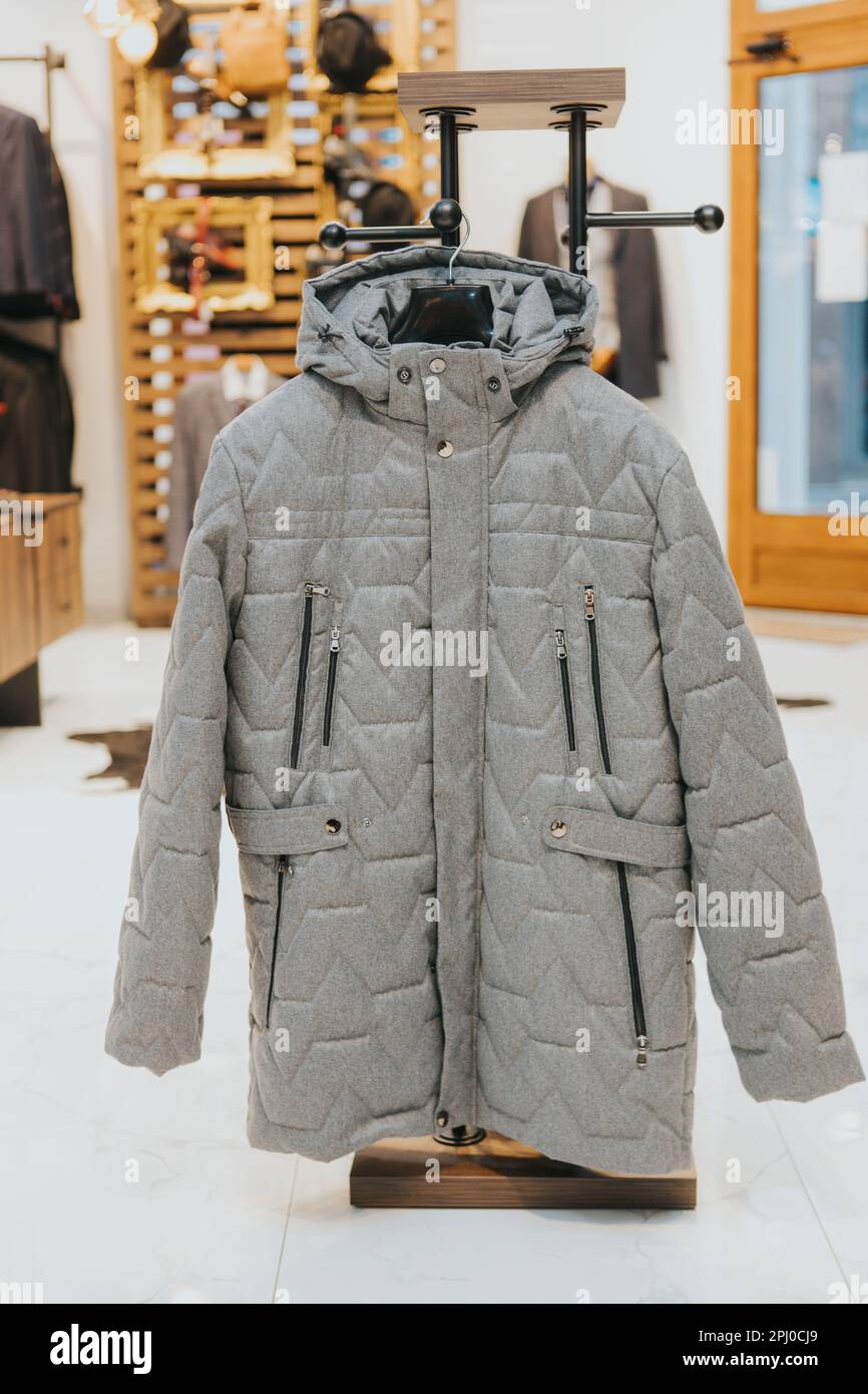 A vertical image of a stylish gray winter coat hanging on a hanger in a ...