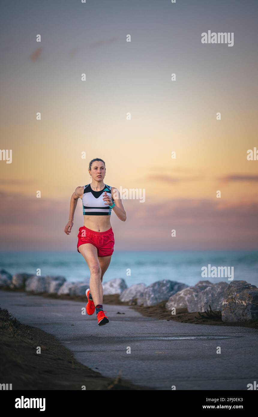 Woman running on a beautiful path with a sunset Stock Photo - Alamy