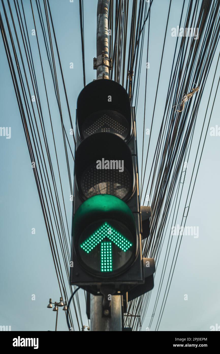 A vertical low-angle shot of a street light with a vivid green arrow ...