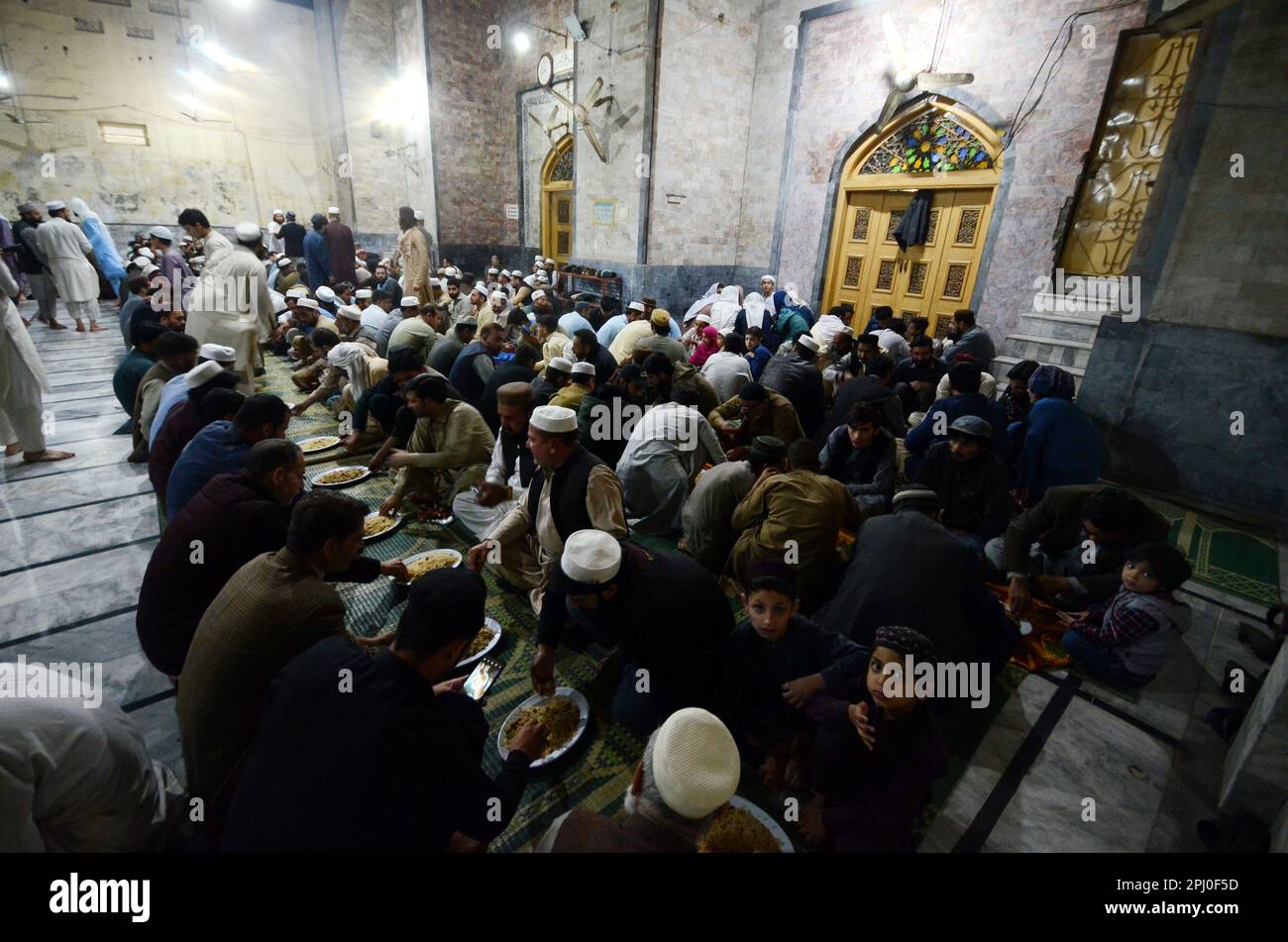 Peshawar, Pakistan. 30th Mar, 2023. People are praying and eating rice ...