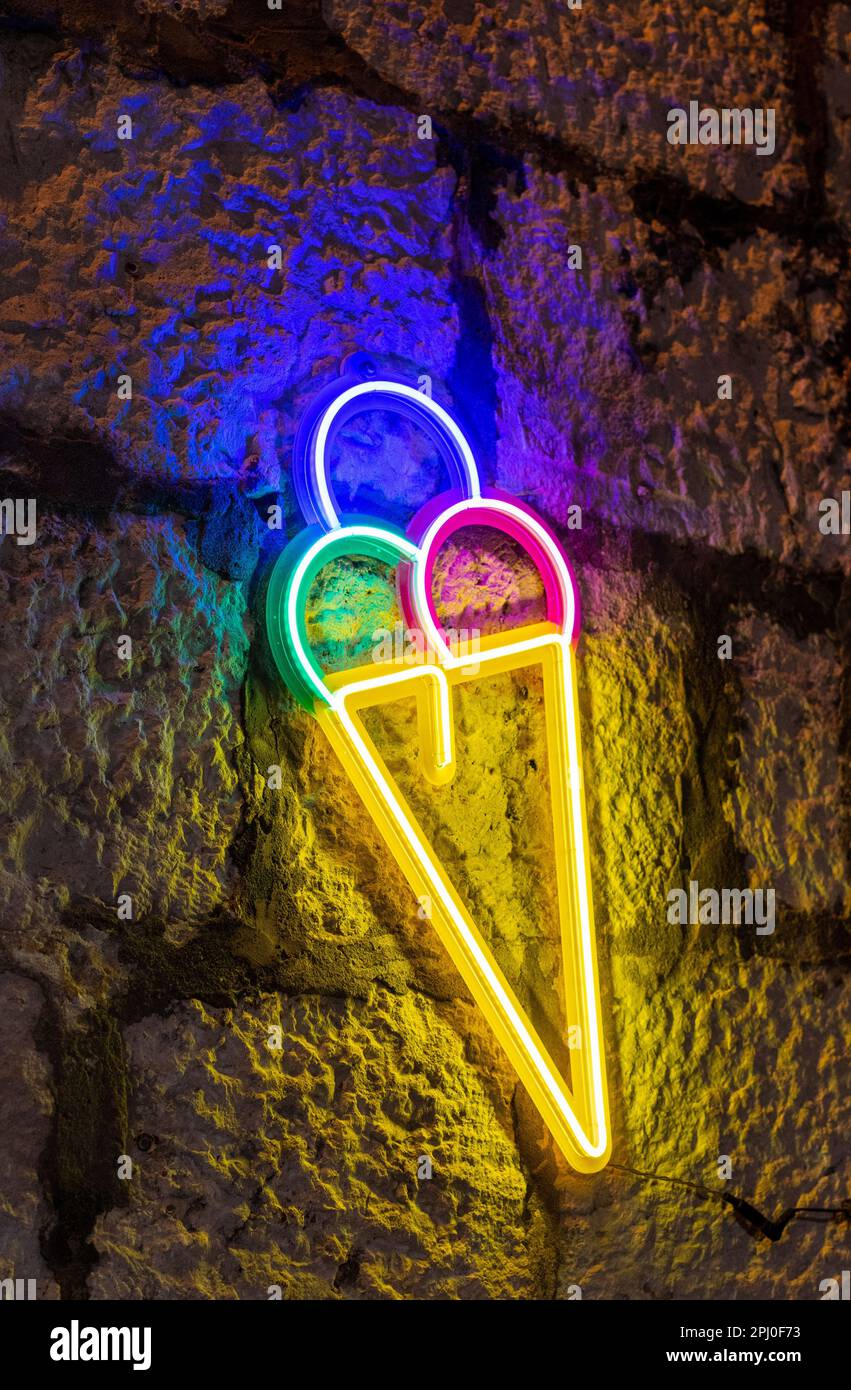 A vibrant, illuminated neon sign in the shape of an ice cream cone ...