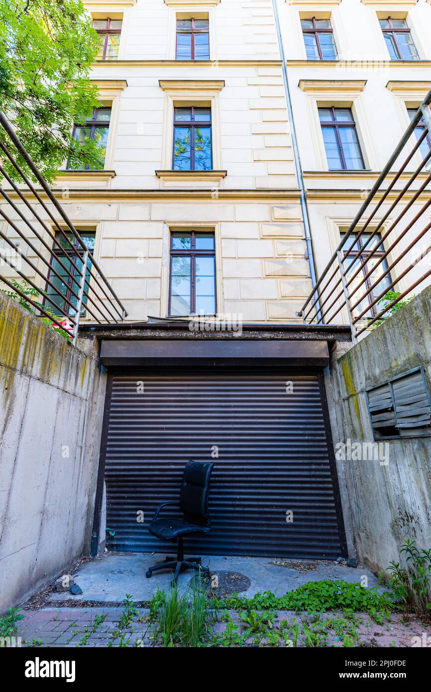 Wroclaw, Poland - June 2022: An old leather office chair standing in front of an old garage door ...