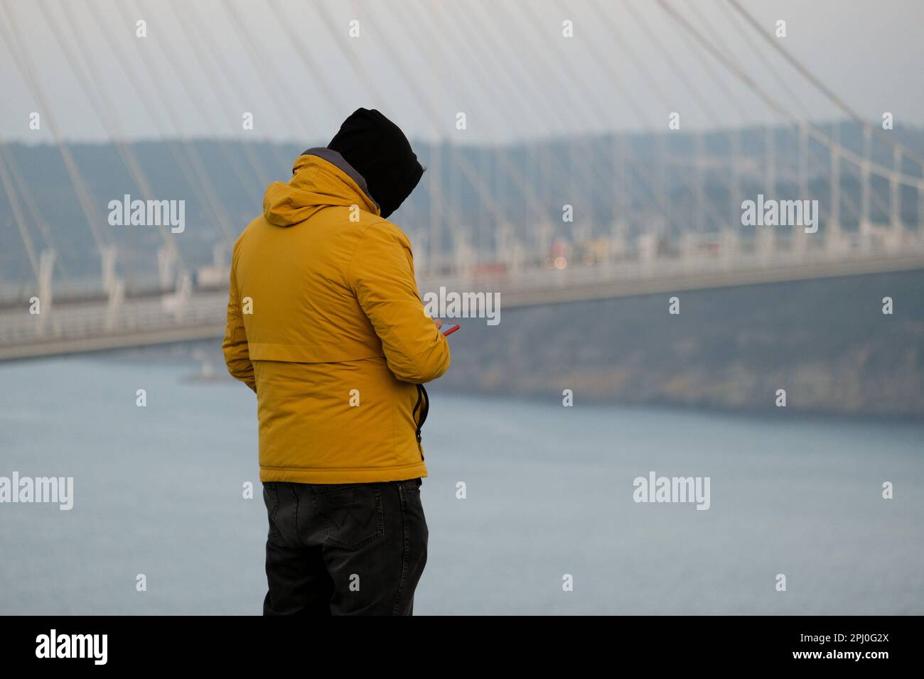 A man who holding phone and not showing face is standing against sea ...