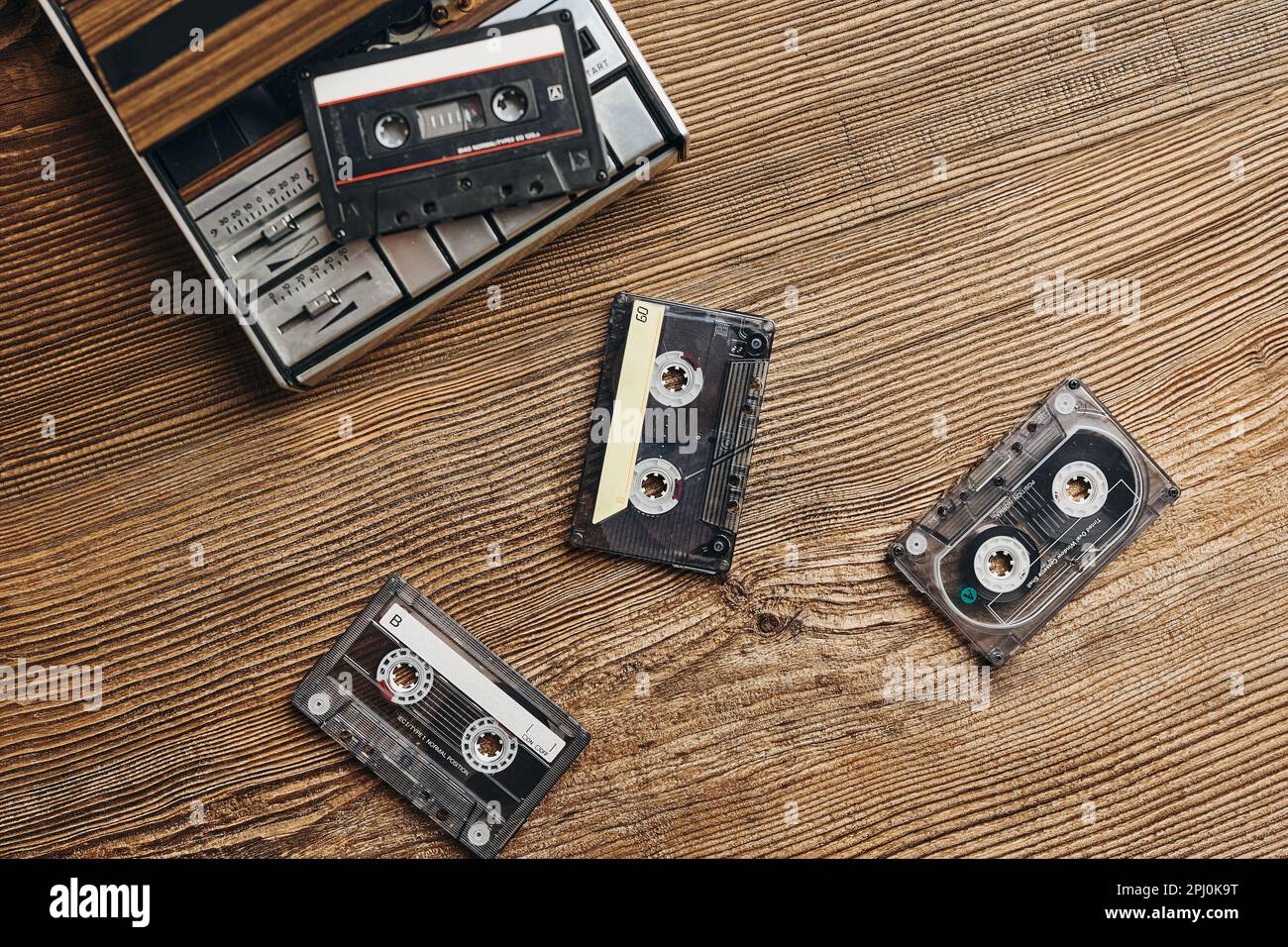 Compact cassette tapes and cassette recorder on wooden table. Retro ...