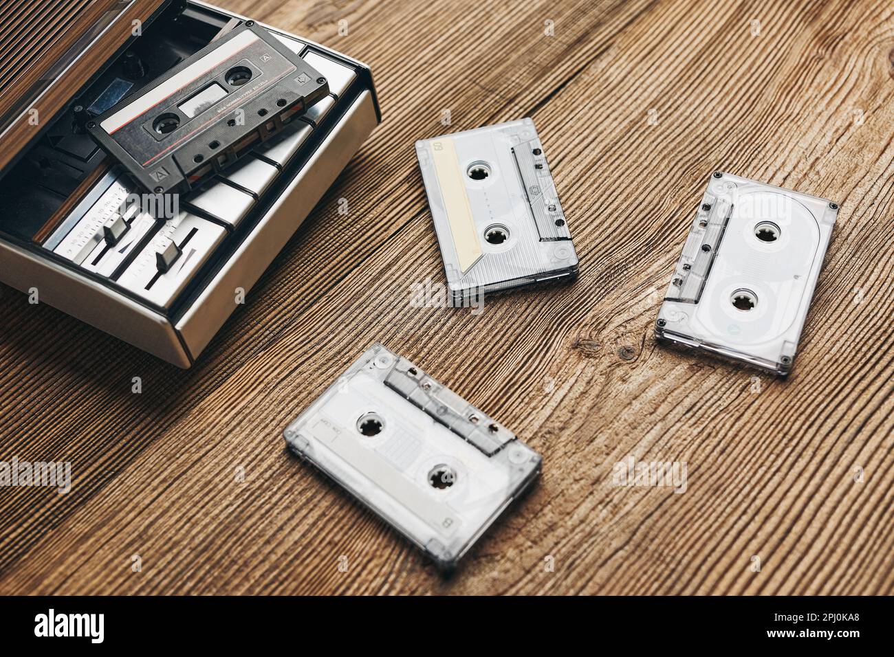 Compact cassette tapes and cassette recorder on wooden table. Retro ...