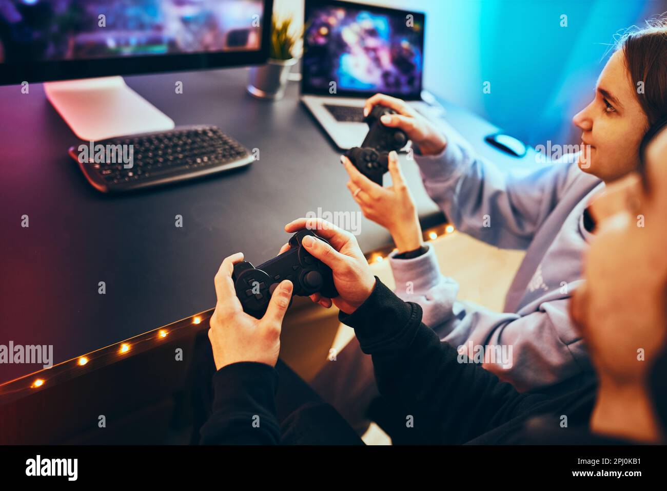 Friends playing video game at home. Gamers holding gamepads sitting at ...