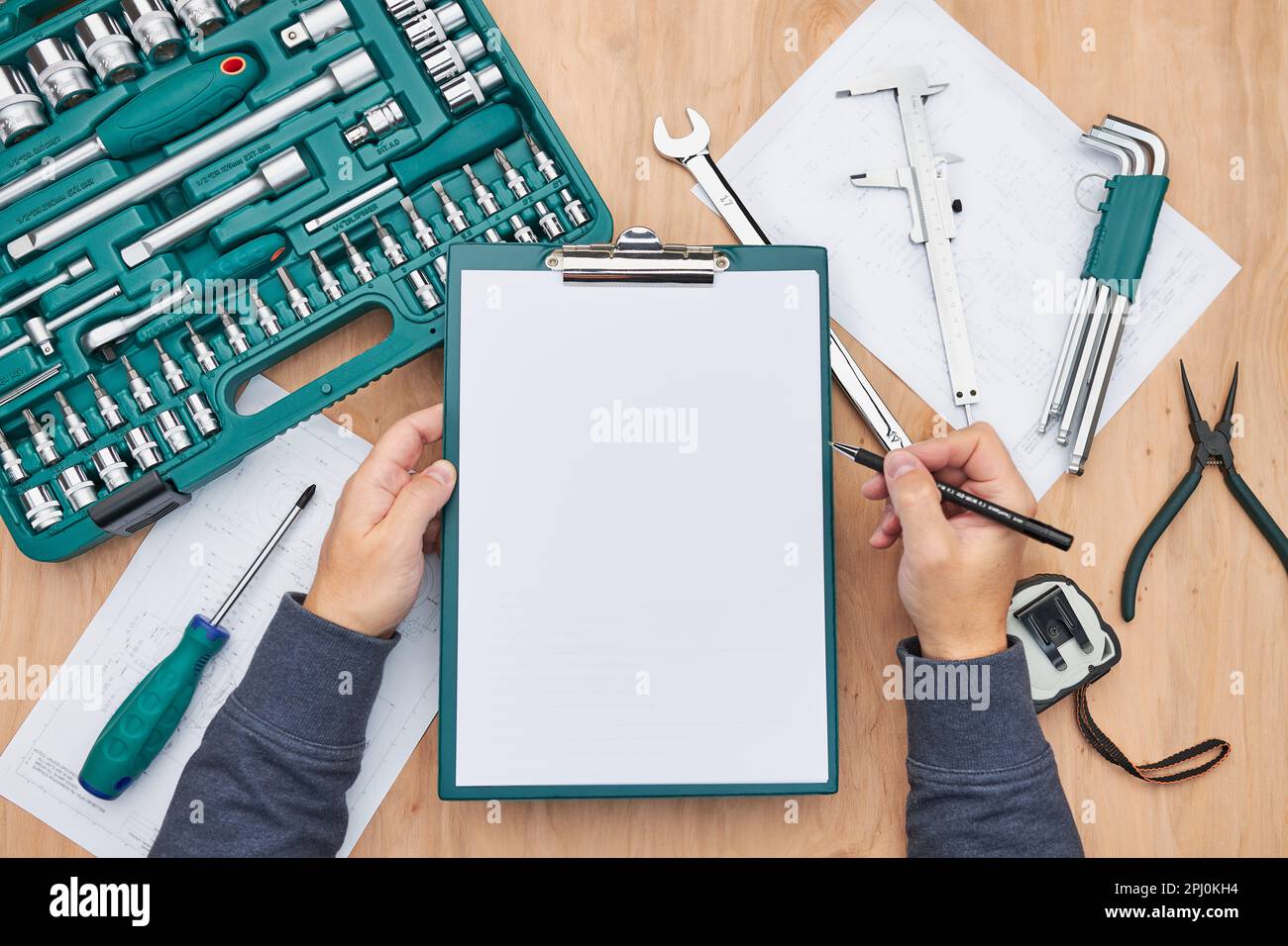 Man working in workshop holding clipboard using many tools. Wrench ...