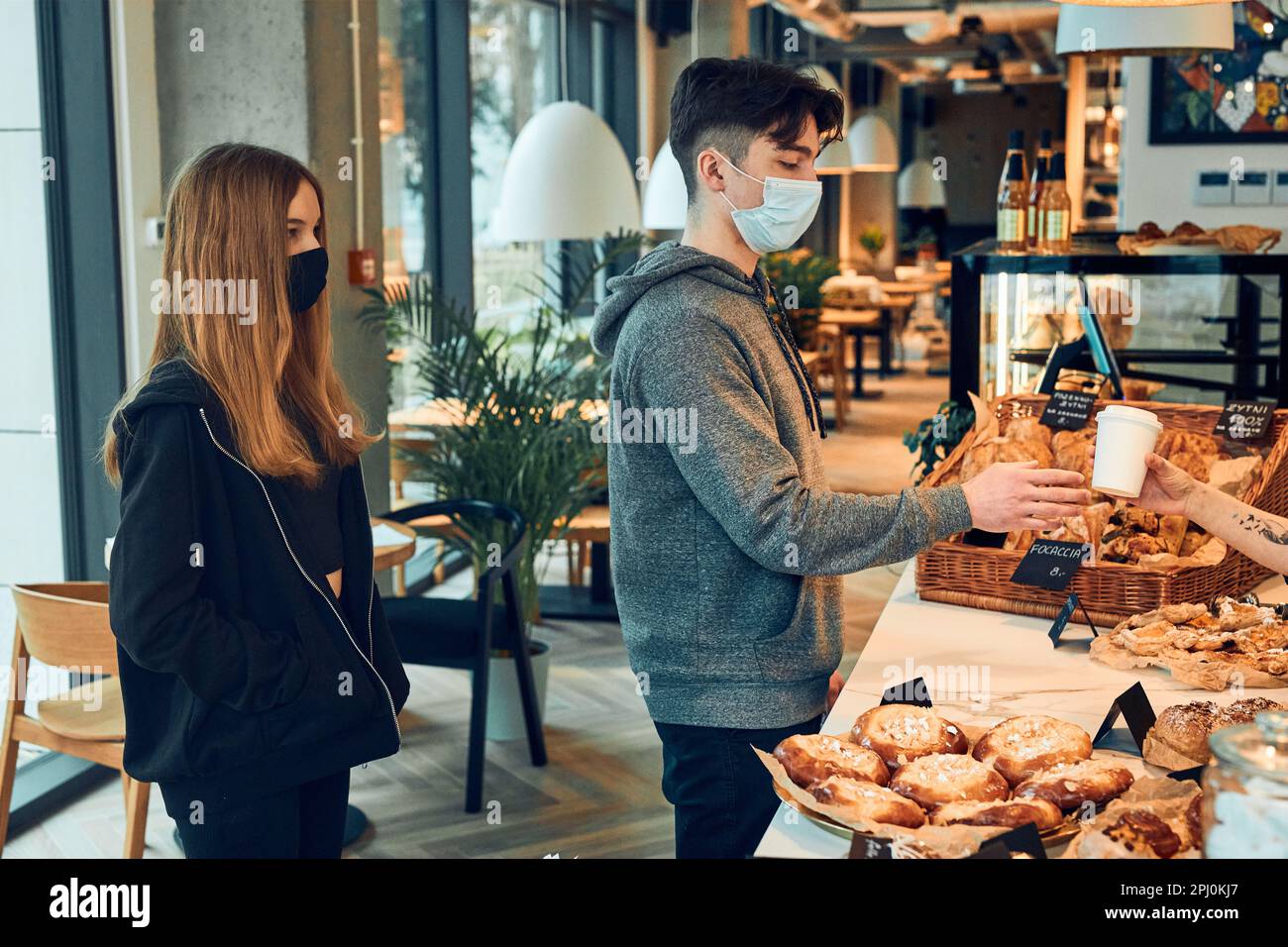 People standing in a queue to buy coffee and pastry in the coffee shop ...