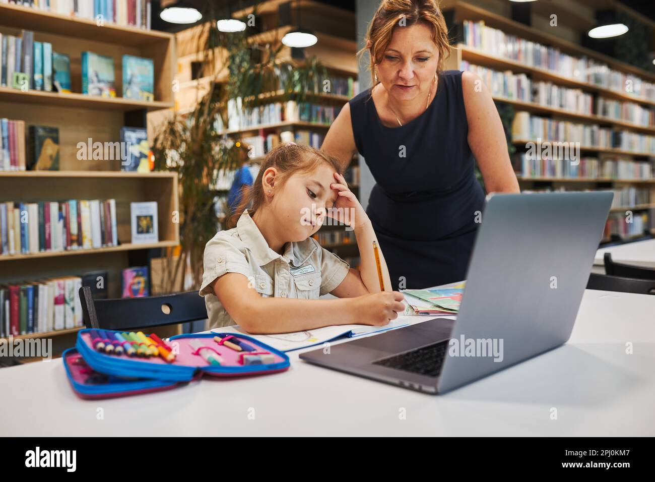 Teacher helping to solve and finish task. Bored little student girl ...