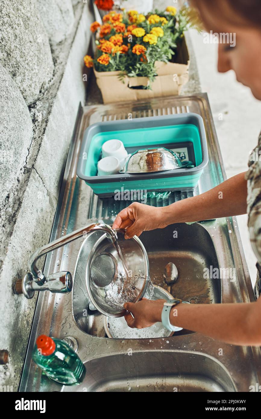 Woman washing up the dishes pots and plates in the outdoor kitchen ...